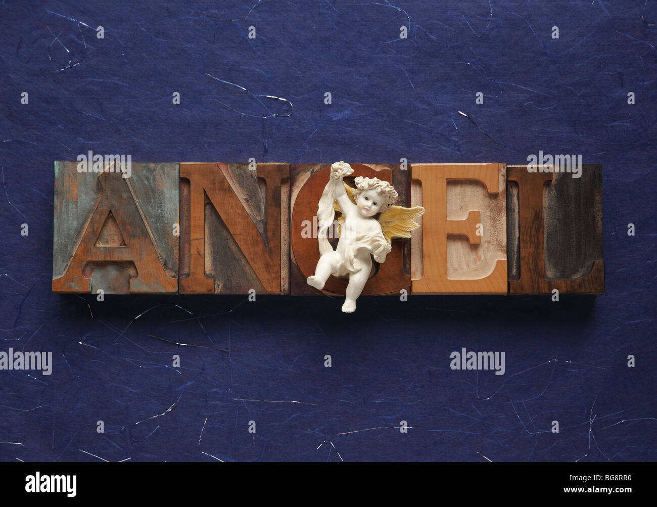 a small angel figure on top of the word angel in old wood type Stock ...