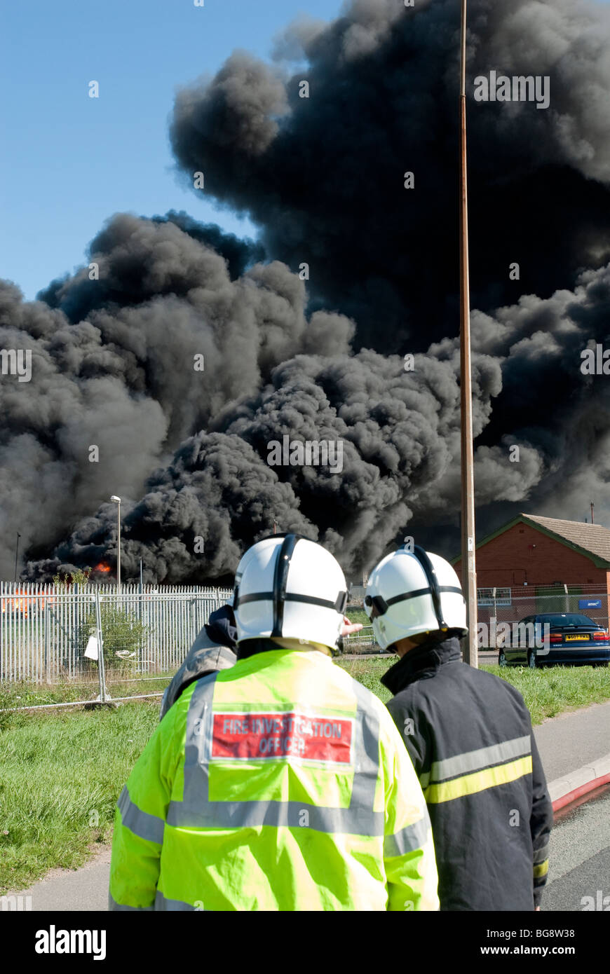 Huge plume of black smoke against blue sky from factory fire with fire ...