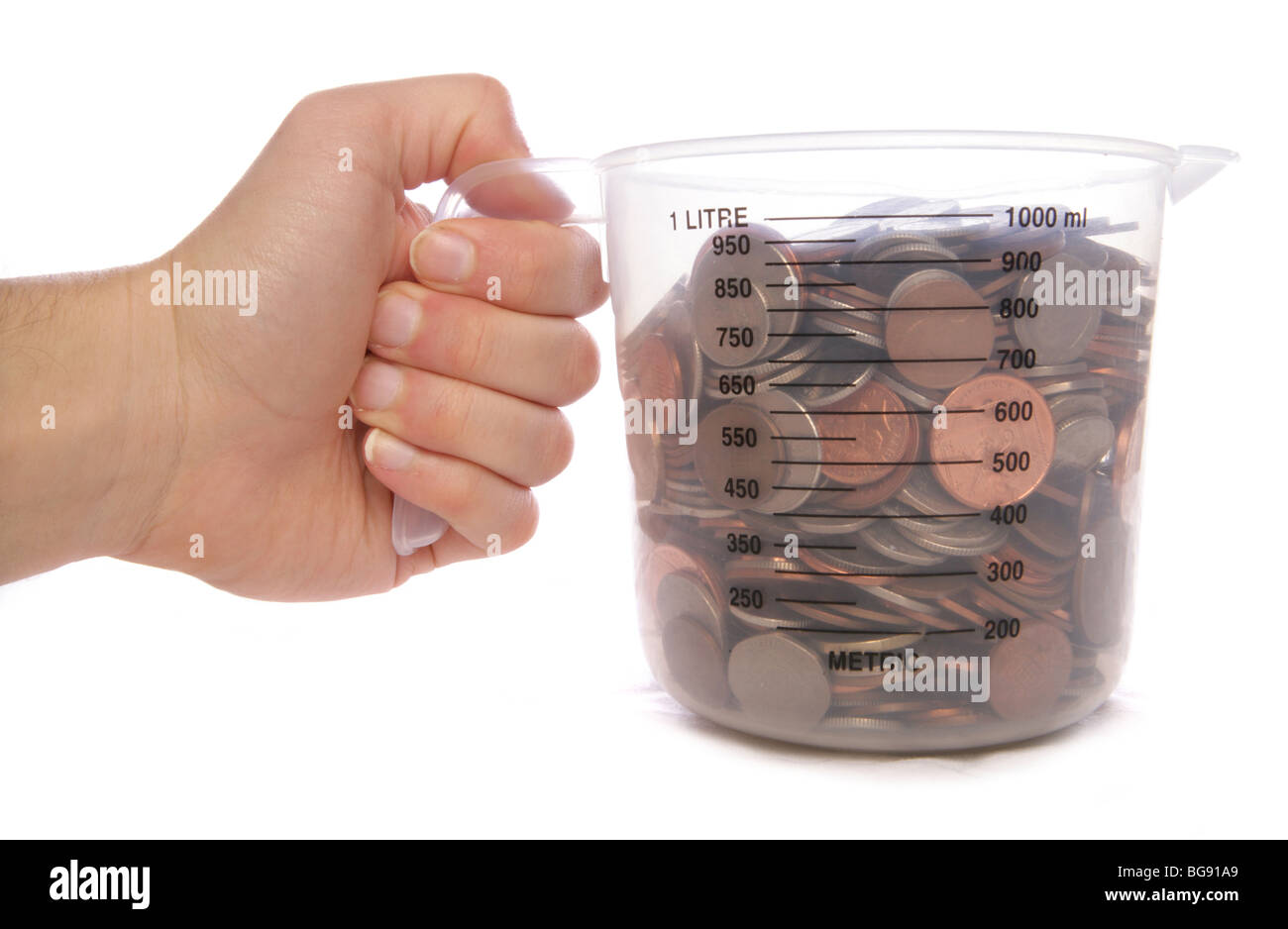 Hand holding measuring jug of money studio cutout Stock Photo - Alamy