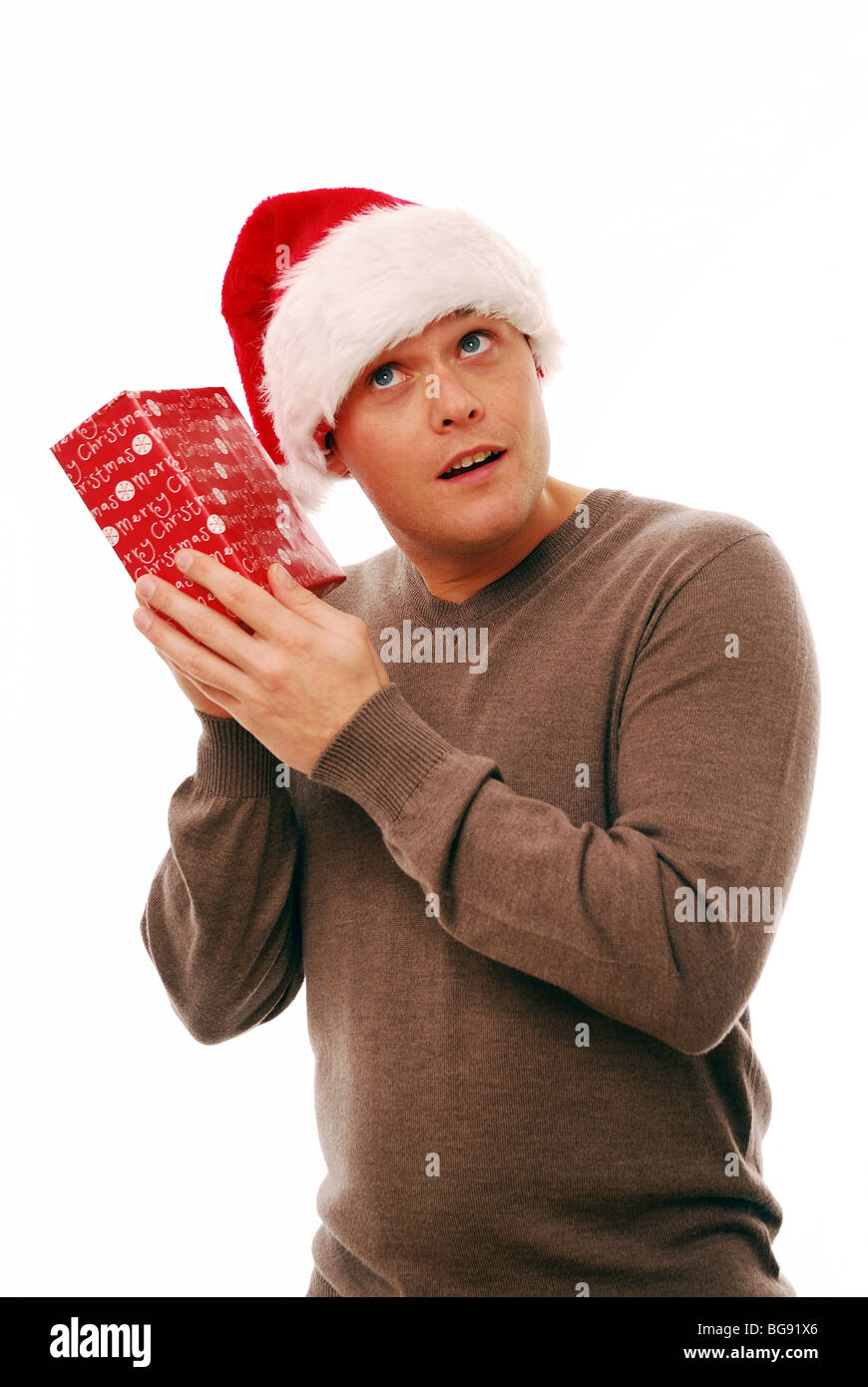 Young man shaking a Christmas present Stock Photo - Alamy