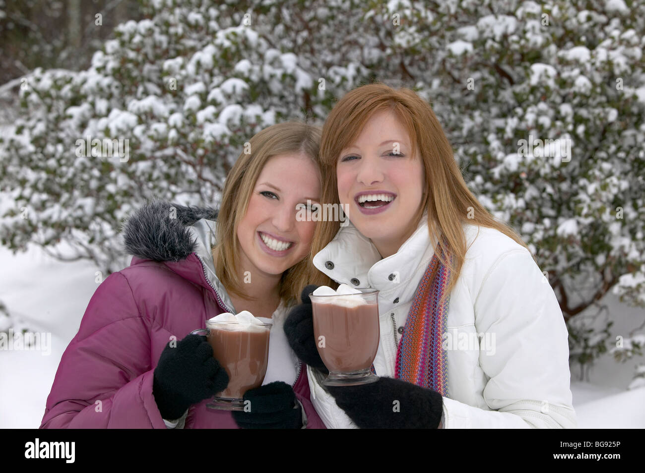 Two girls drinking hot chocolate outside in the snow Stock Photo - Alamy
