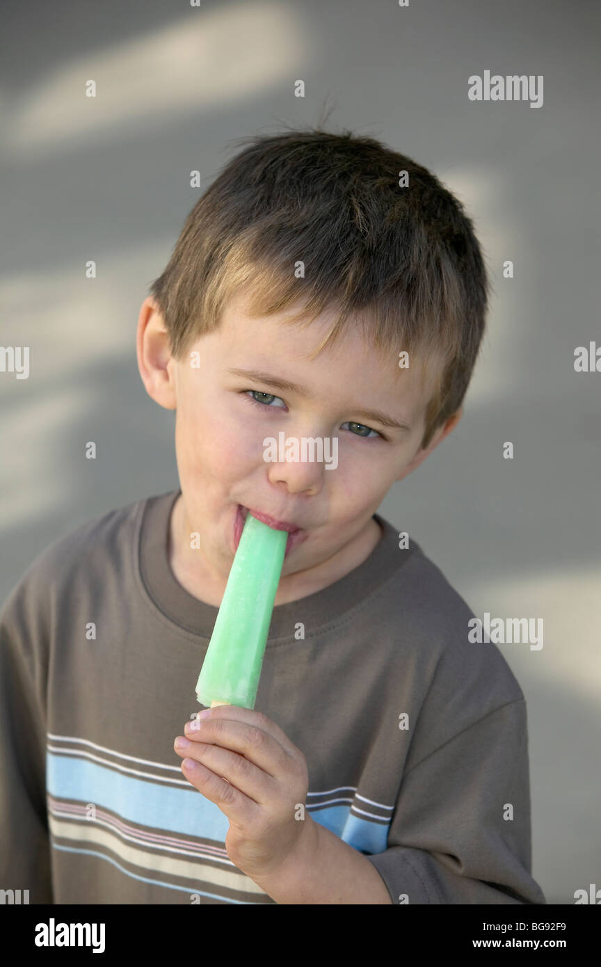 Boy eating lime popsicle Stock Photo - Alamy