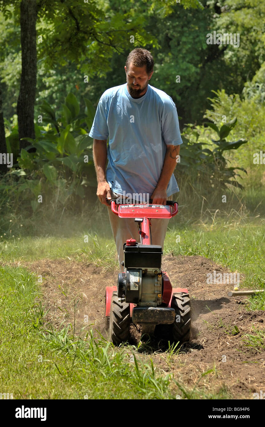 Man plowing up soil with a garden tiller Stock Photo - Alamy