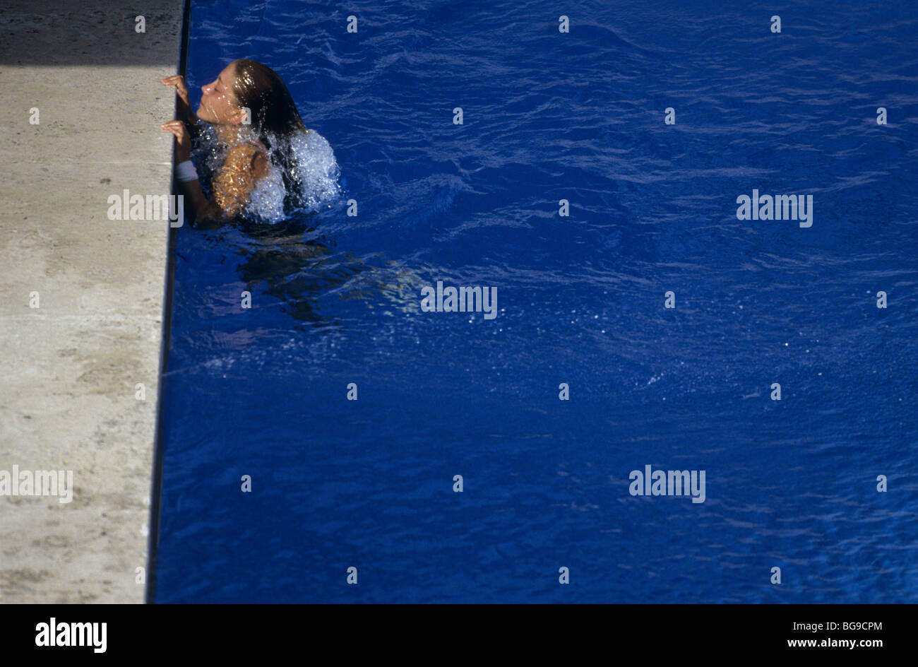 Swimmer surfaces at edge of pool Stock Photo - Alamy