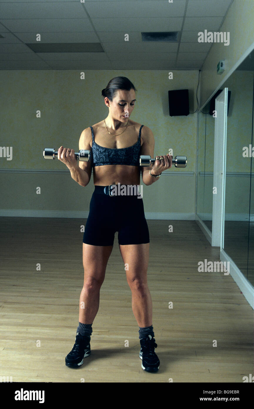 Woman working with a pair of hand weights in a gym Stock Photo - Alamy