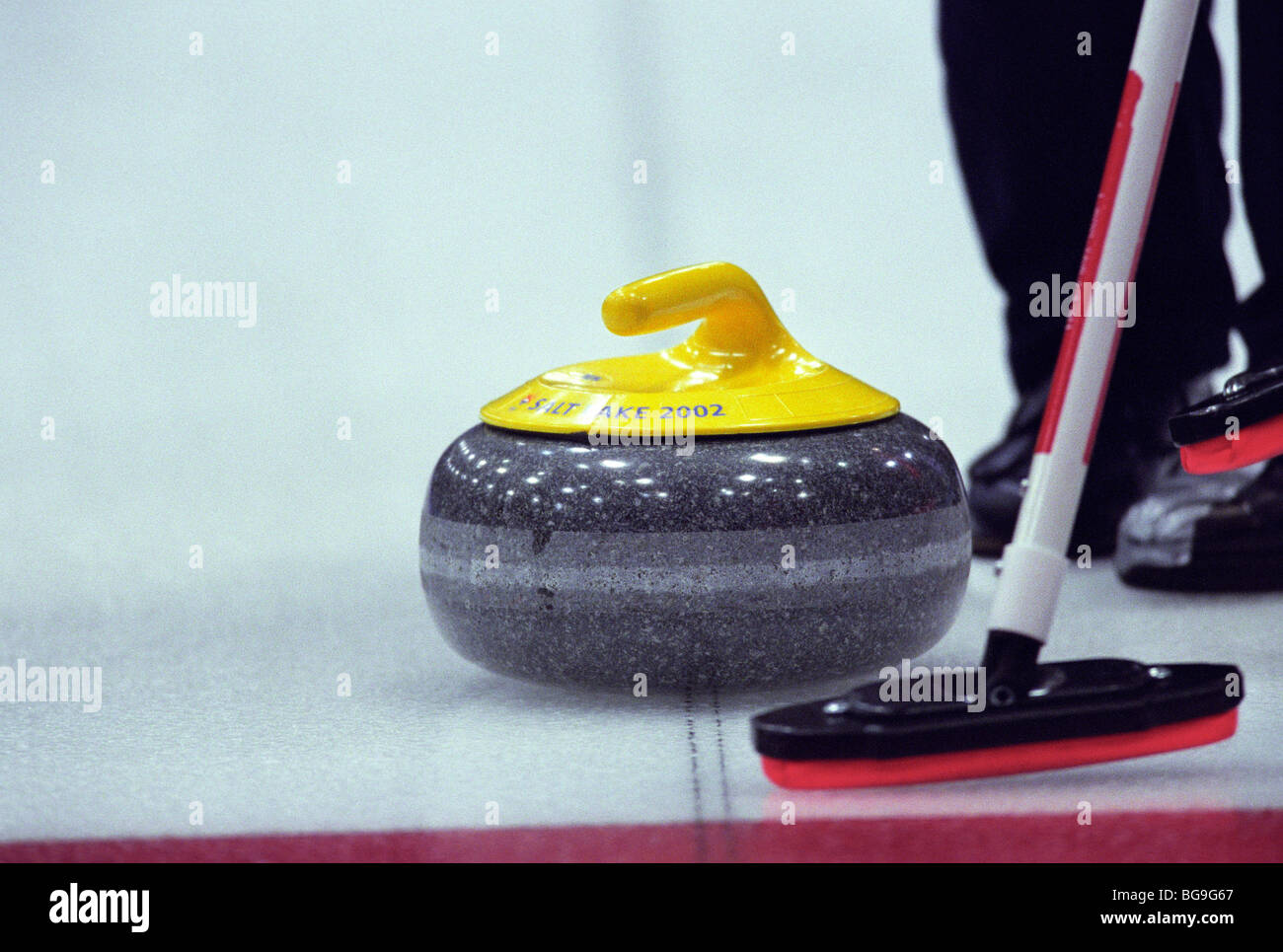 Curler sweeping path of curling stone Stock Photo - Alamy