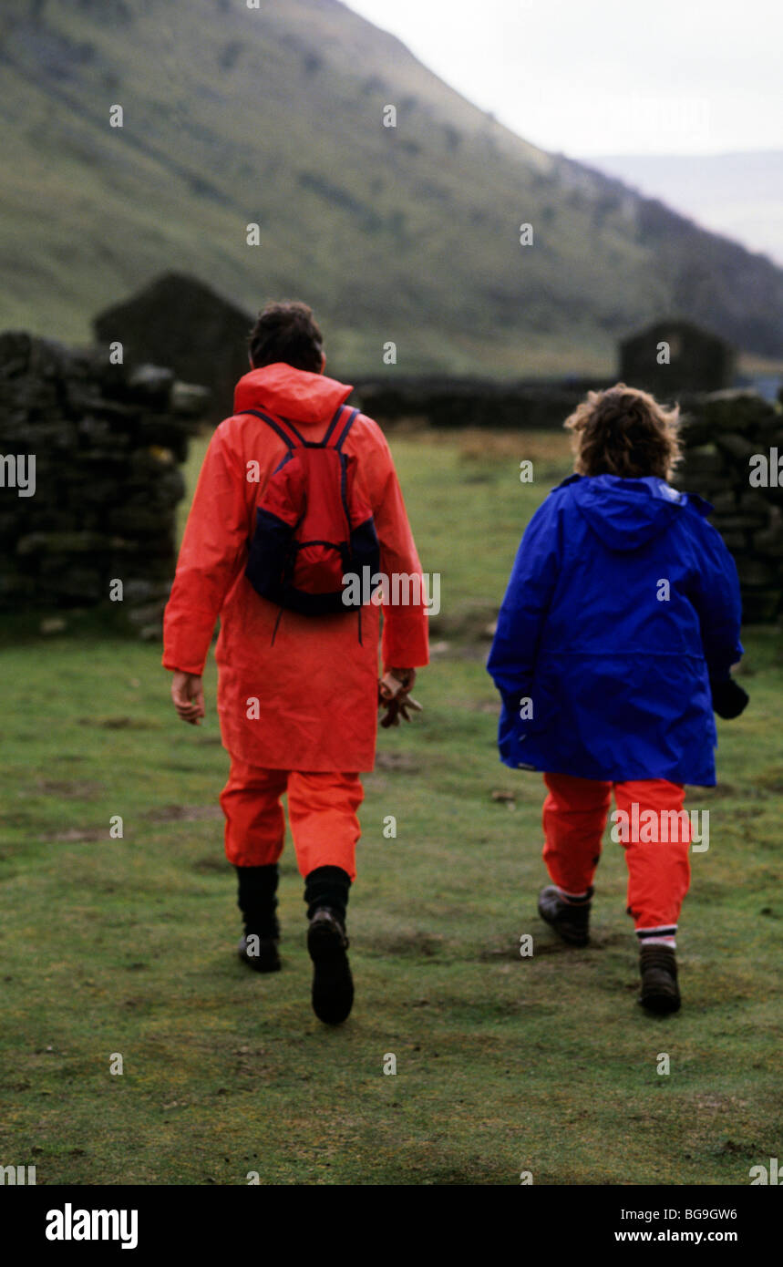 Man and woman walkers approaching an opening in a stone wall Stock ...
