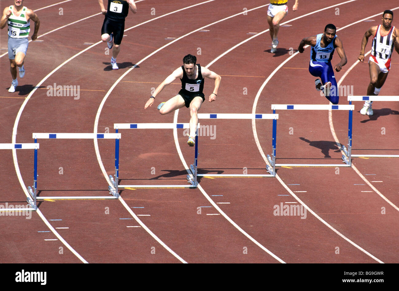 Group of male runners jumping over hurdles Stock Photo - Alamy