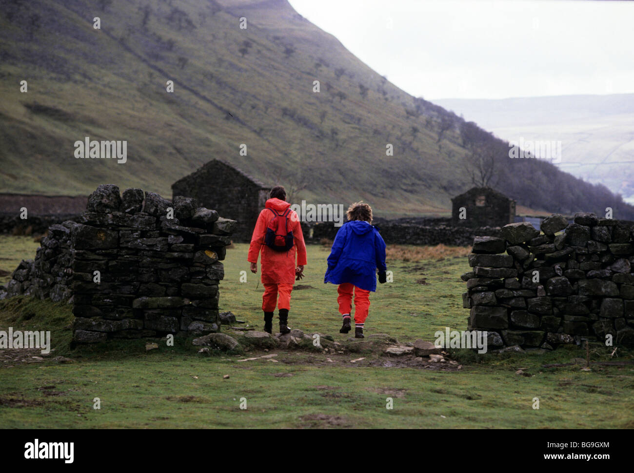 Man and woman walkers walking through a derelict stone wall Stock Photo ...