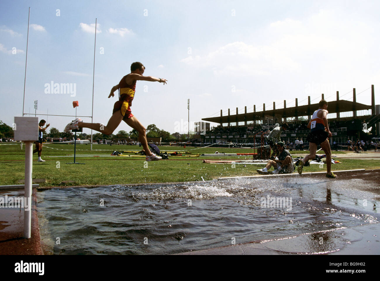 Group of male runners jumping over hurdles during a steeplechase Stock ...