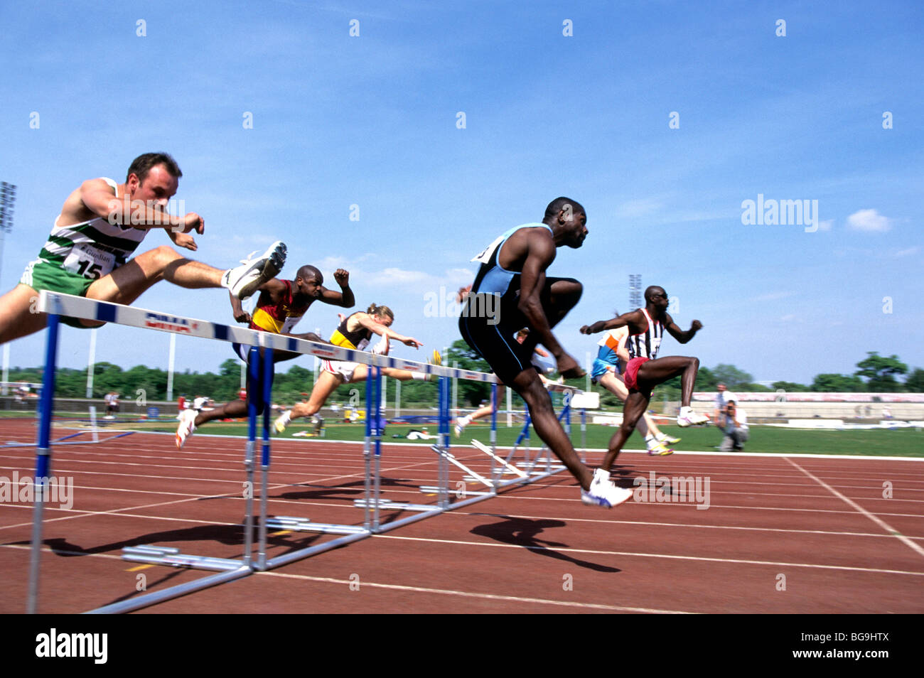 Group of male runners jumping over hurdles Stock Photo - Alamy