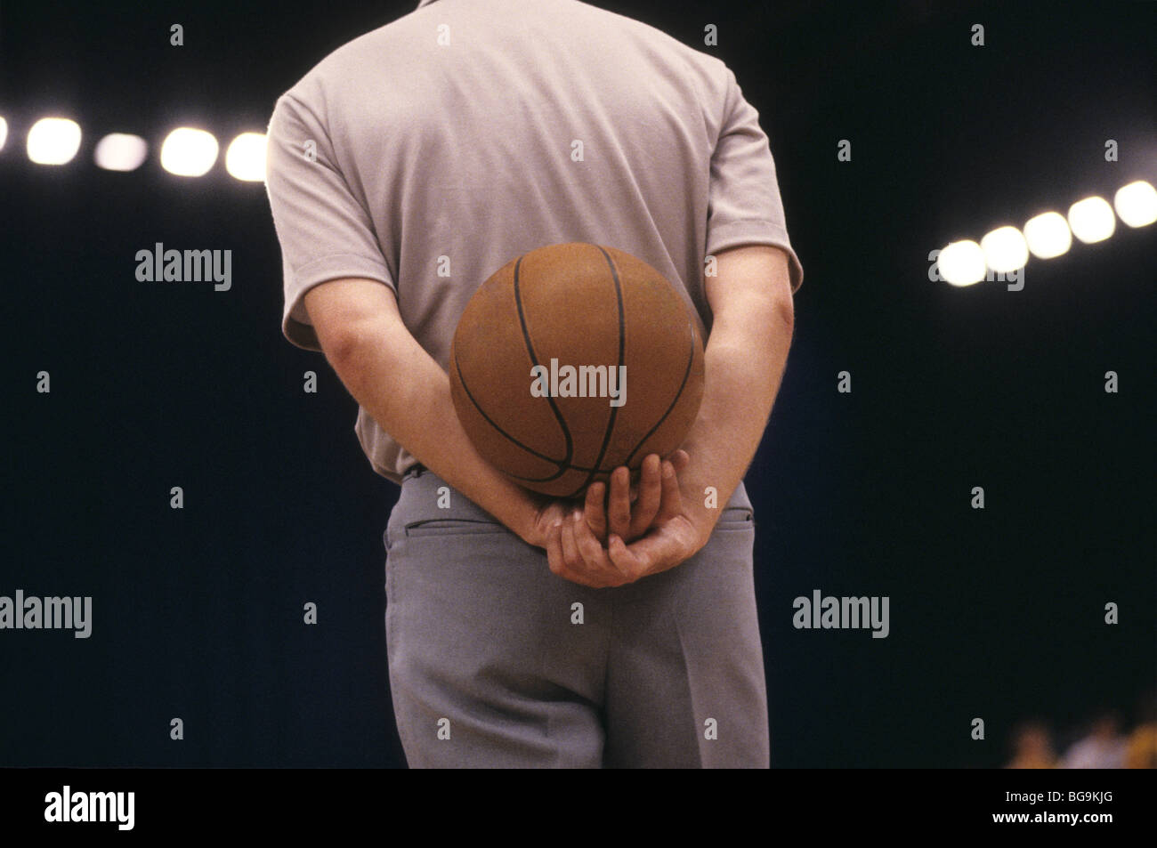 Referee holding basketball behind his back Stock Photo - Alamy