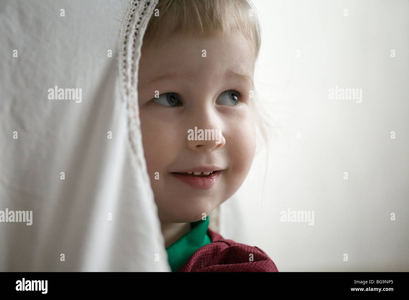 little girl with the opened look behind window curtain Stock Photo - Alamy