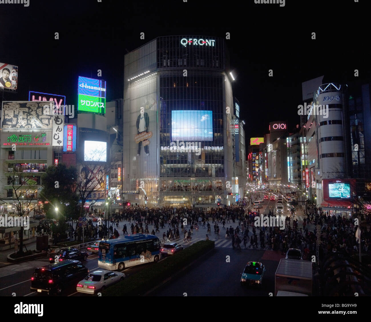 A crowd of pedestrians crosses the street at Shibuya Crossing at night ...