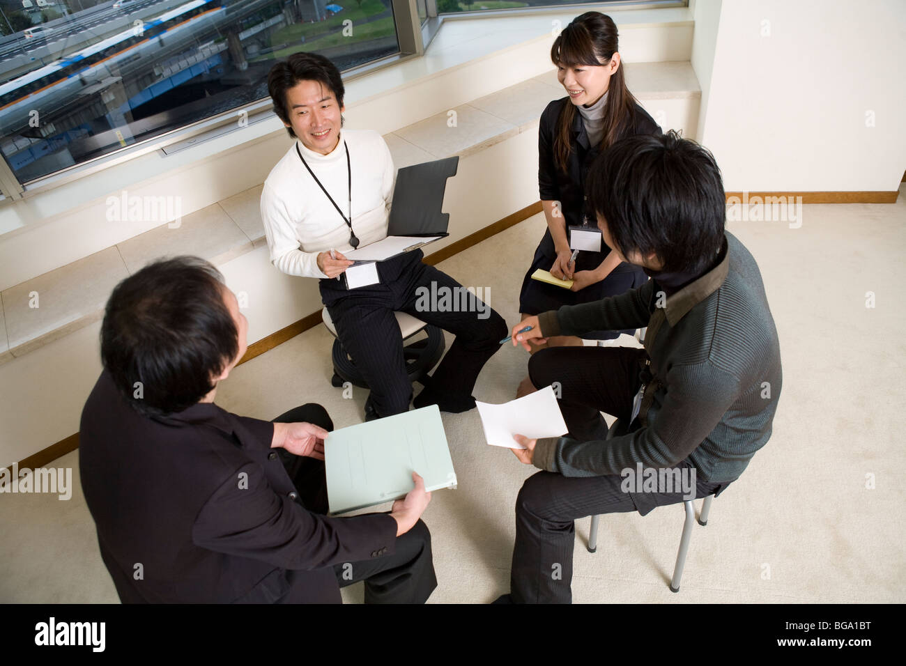 Four people meeting by window Stock Photo - Alamy