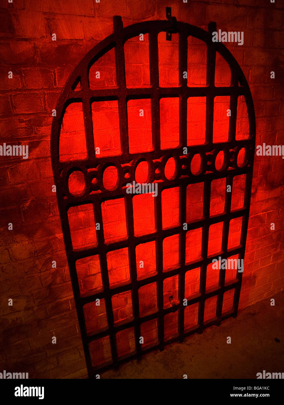 A large metal prison gate against the backdrop of bright red light ...