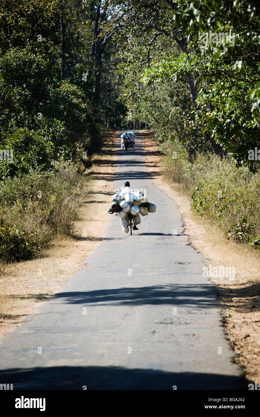 Man transporting pots and pans by a bike on a rural road in Orissa ...