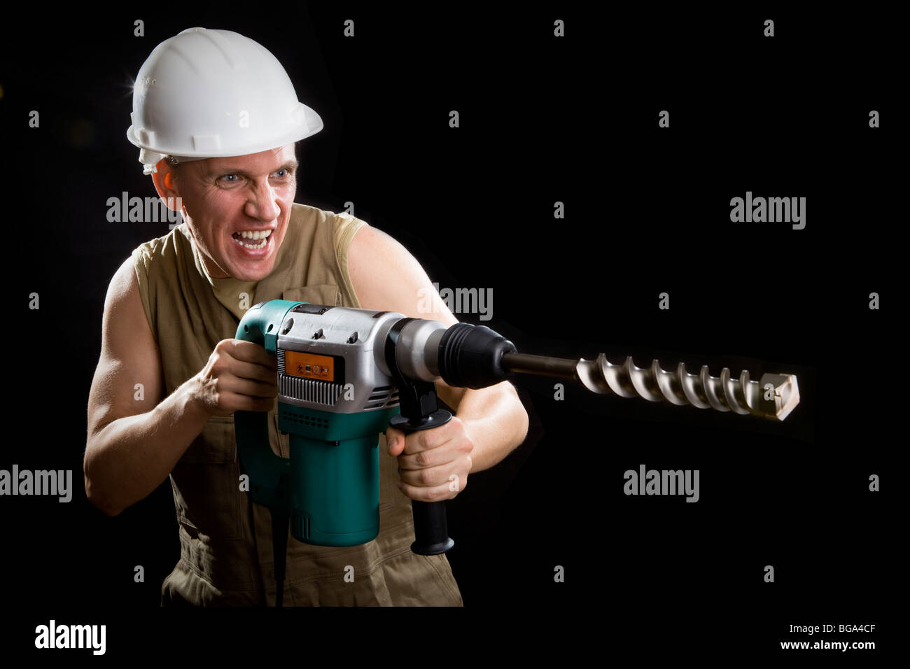The builder in a protective helmet holds the professional puncher ...
