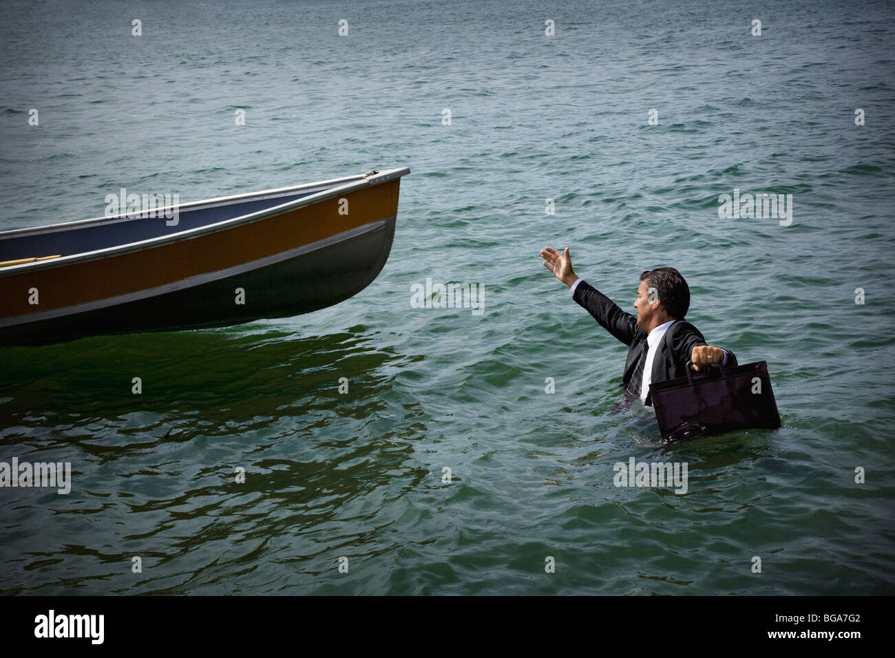 Businessman wading through water towards boat Stock Photo - Alamy