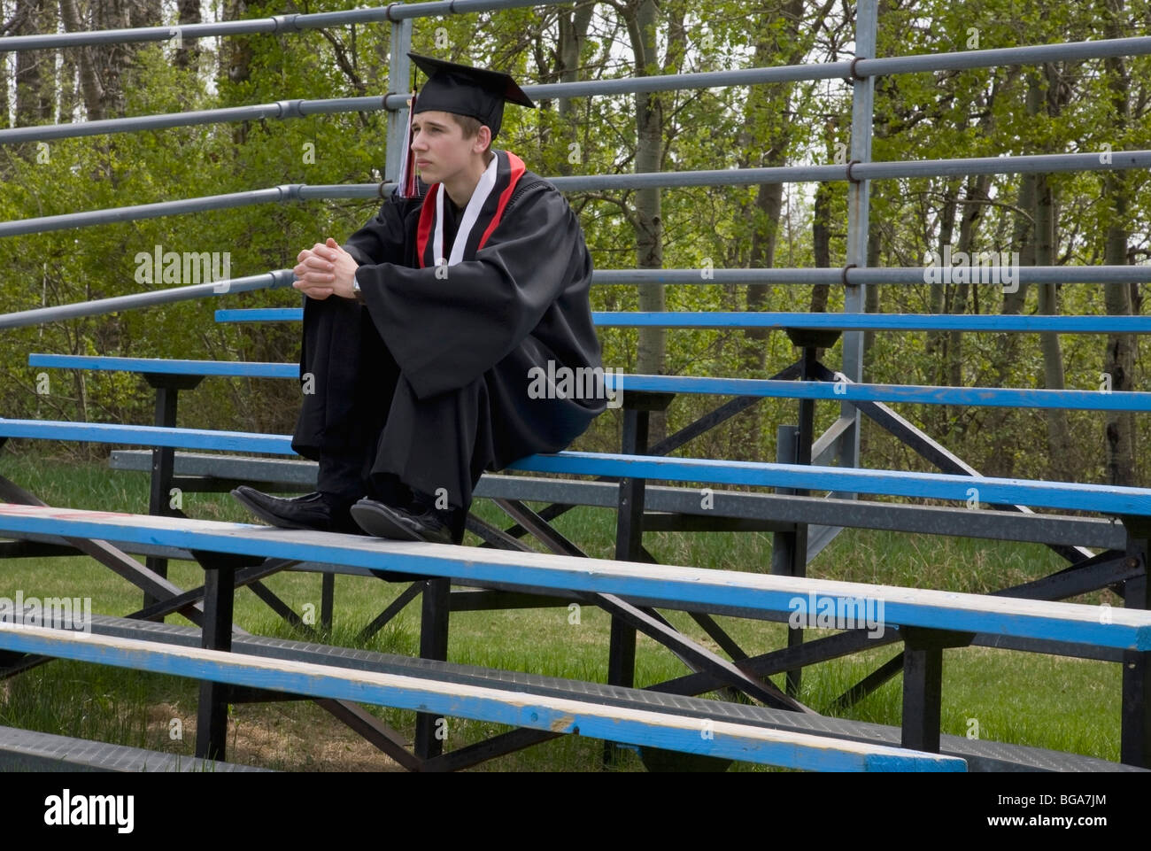 Graduate sitting on bleachers Stock Photo - Alamy