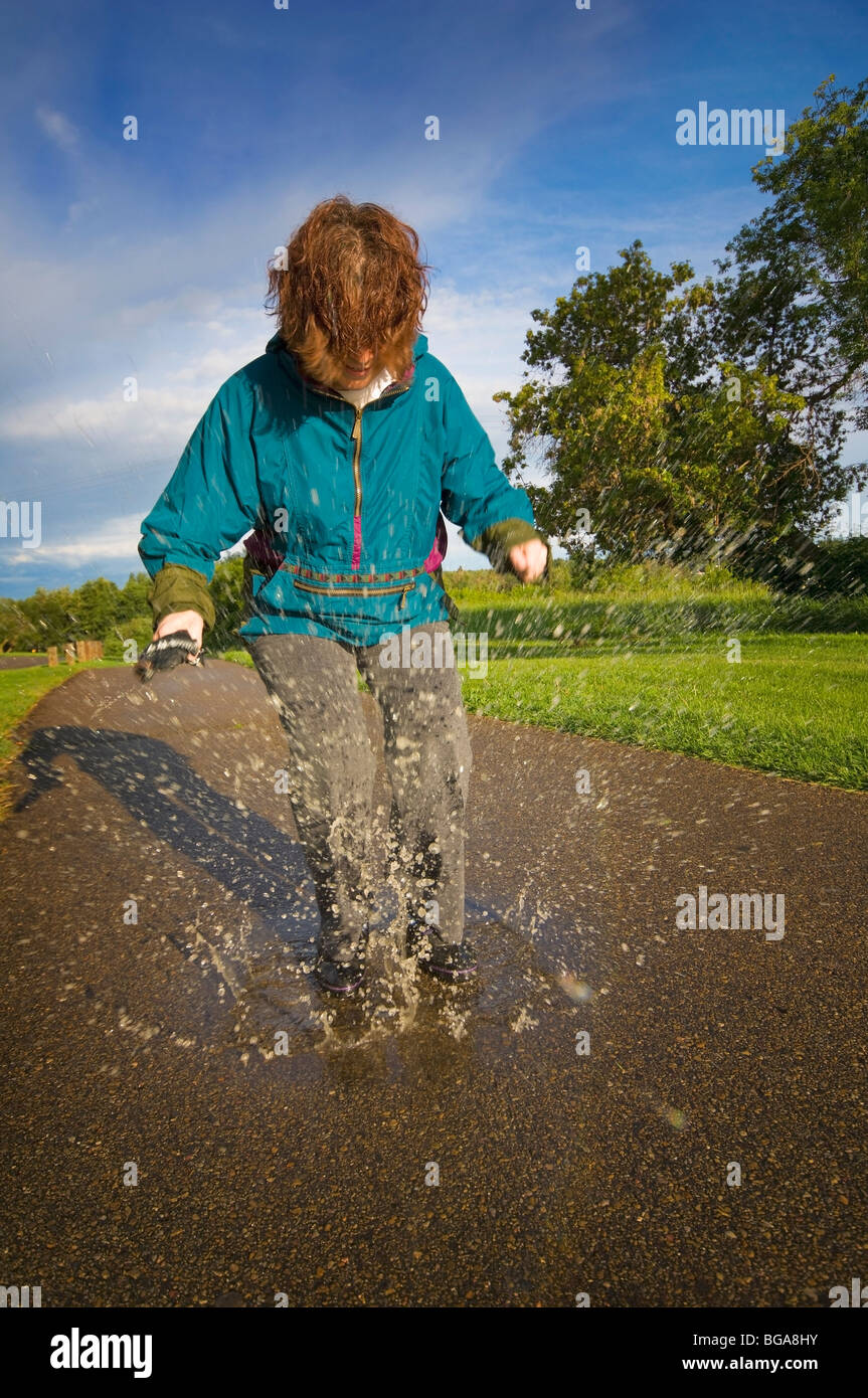Woman playing in the rain puddles Stock Photo - Alamy