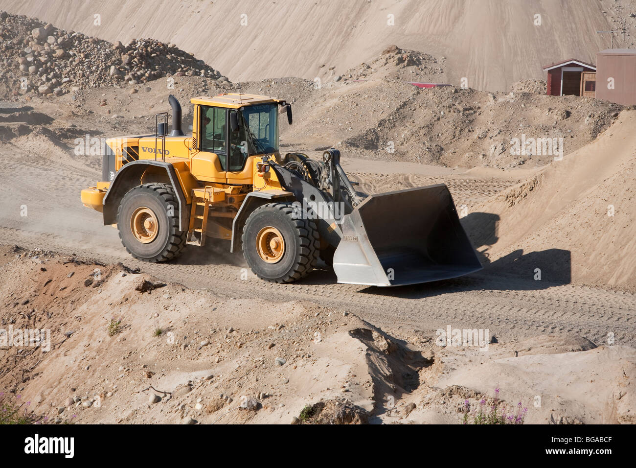 Volvo front loader moving sand in a sandpit at sand quarrying area ...