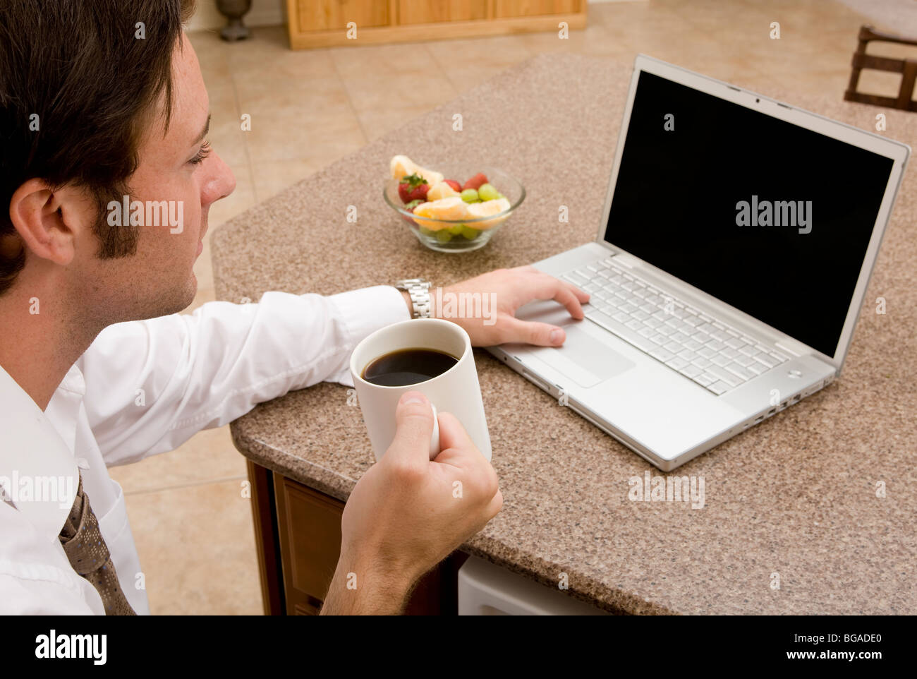 With a morning cup of coffee, a young person checks email and works on ...