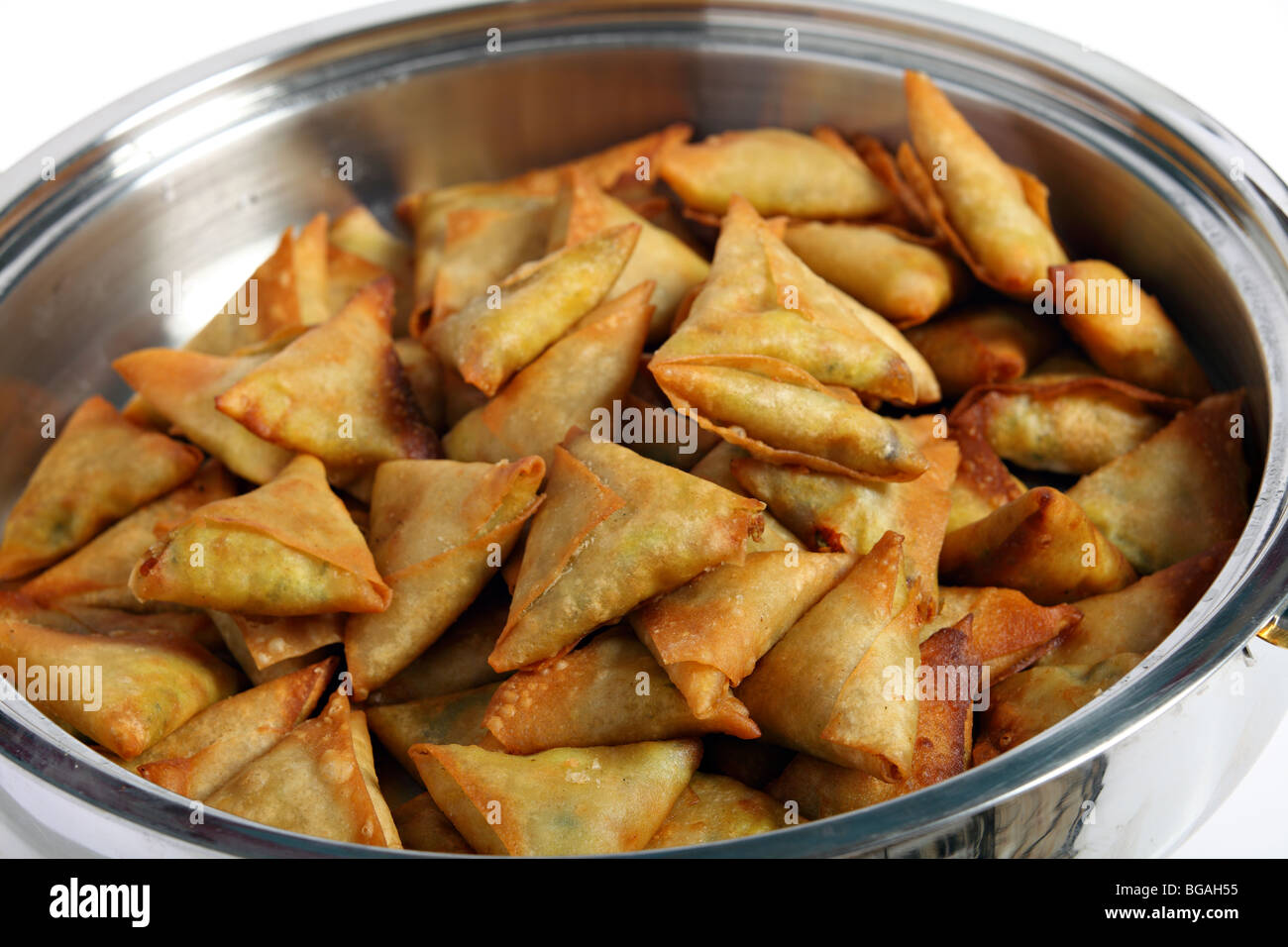 A serving bowl full of fresh vegetable samosas, a popular snack or ...