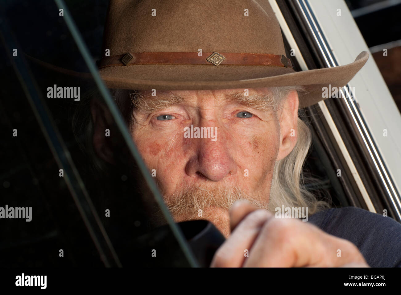 An elderly man with a white beard driving a pickup truck and staring ...