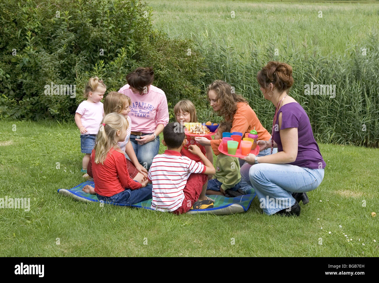 Picnic on daycare center, Child-care workers giving drinks and food to ...
