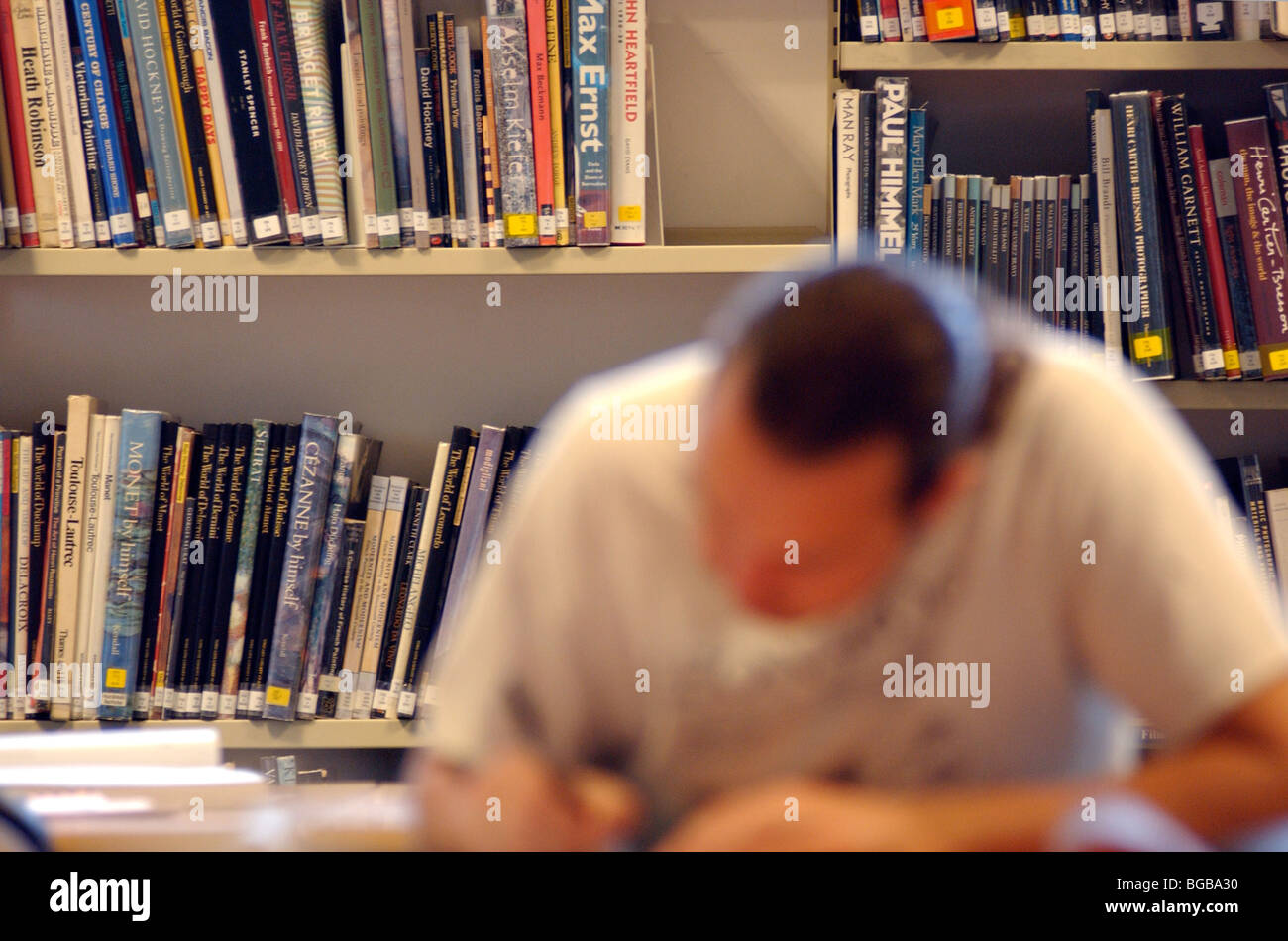 Royalty free photograph of student writing in library with focus on ...