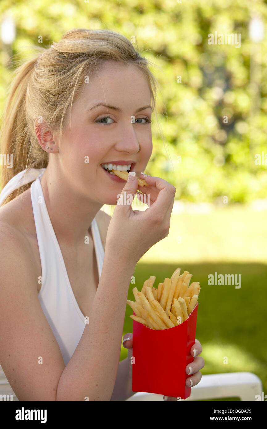 Young woman eating french fries outside Stock Photo - Alamy
