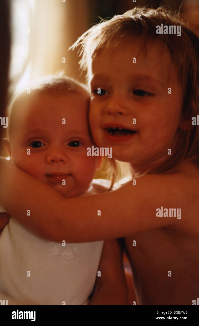 Photograph of young sisters cuddle baby toddlers children family Stock ...