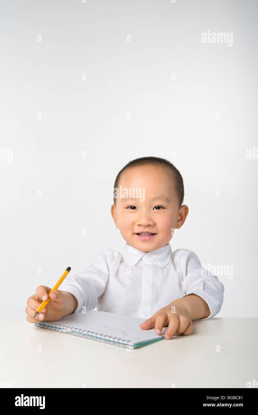 Young boy gets ready to write on a notebook Stock Photo - Alamy