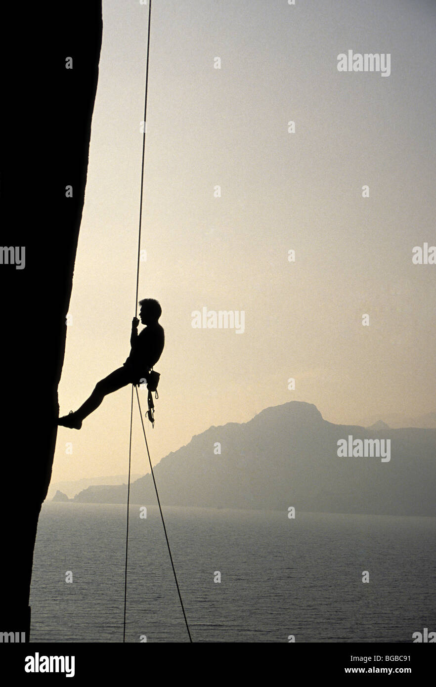 Man abseiling a rock face by a lake Stock Photo - Alamy