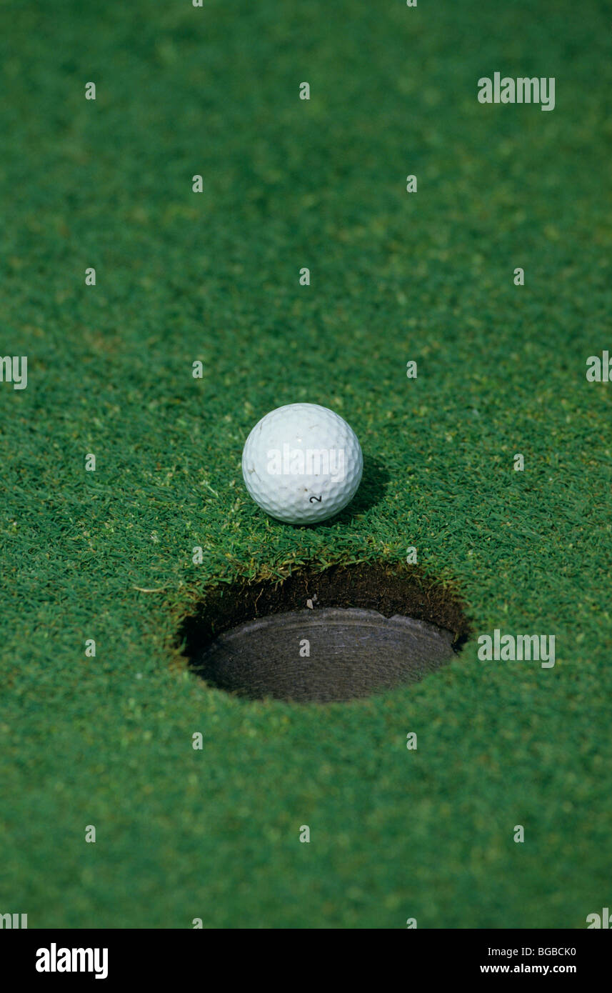 Golf ball by the hole Stock Photo - Alamy
