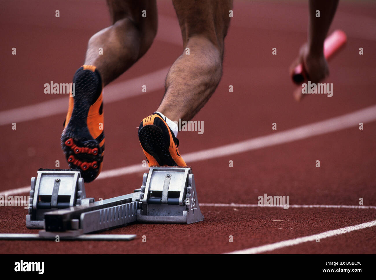 Relay runner taking off from the starting block Stock Photo - Alamy