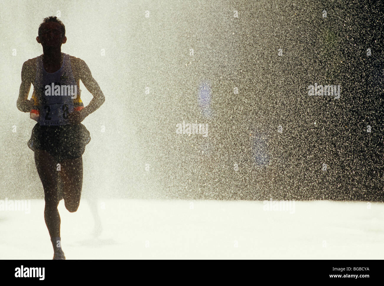 Marathon runner passing through water sprinklers Stock Photo - Alamy