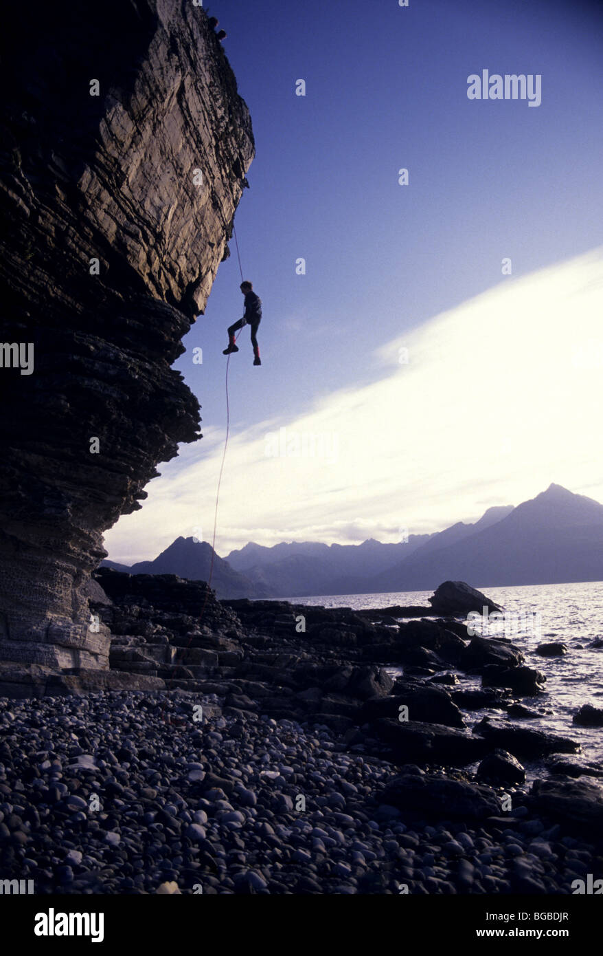 Man abseiling a rock face by a lake Stock Photo - Alamy