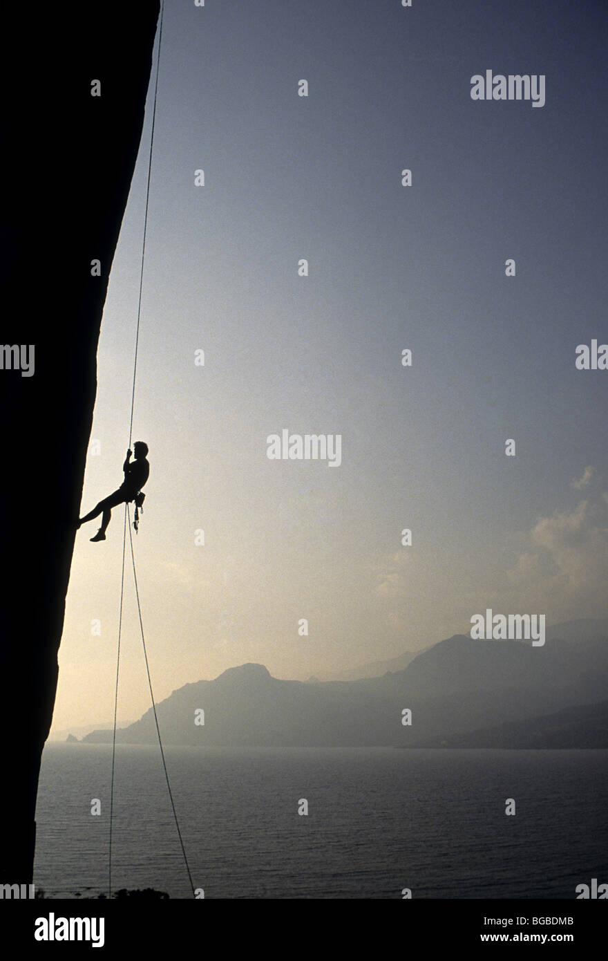 Man abseiling a rock face by a lake Stock Photo - Alamy
