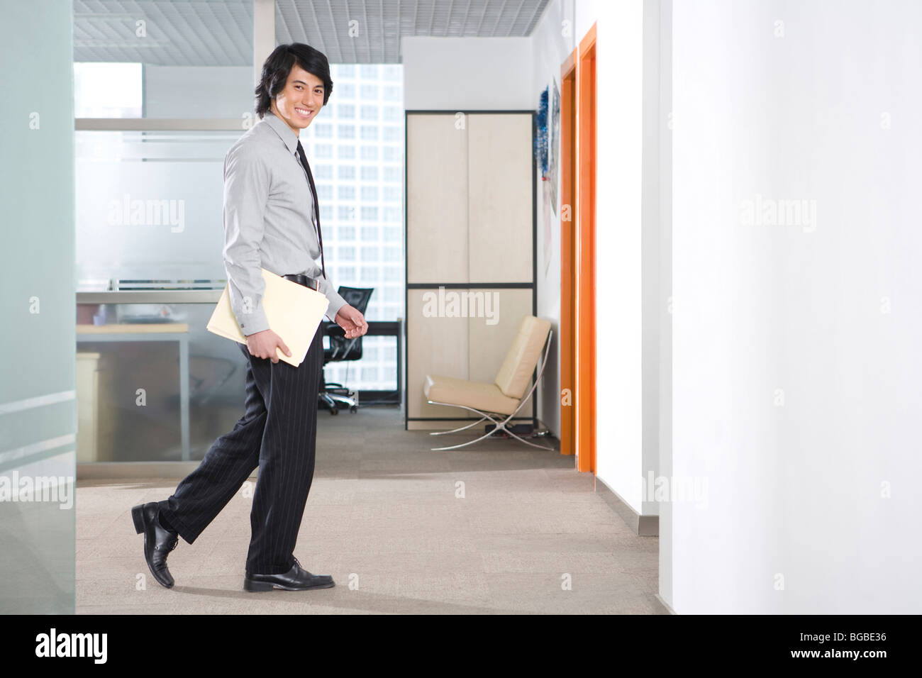 Young businessman walks through office Stock Photo - Alamy