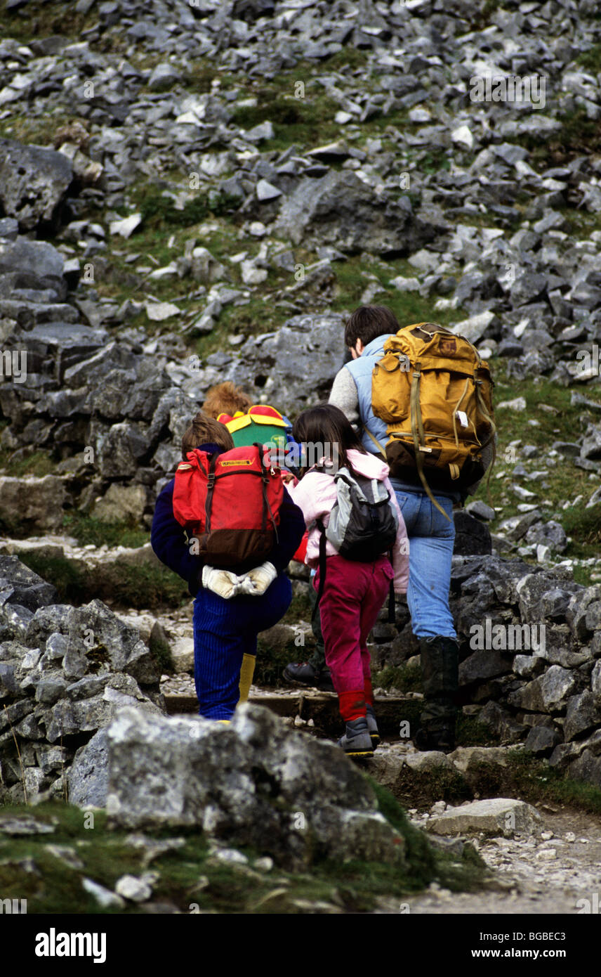 Man and three children climbing up a steep rocky step path Stock Photo ...