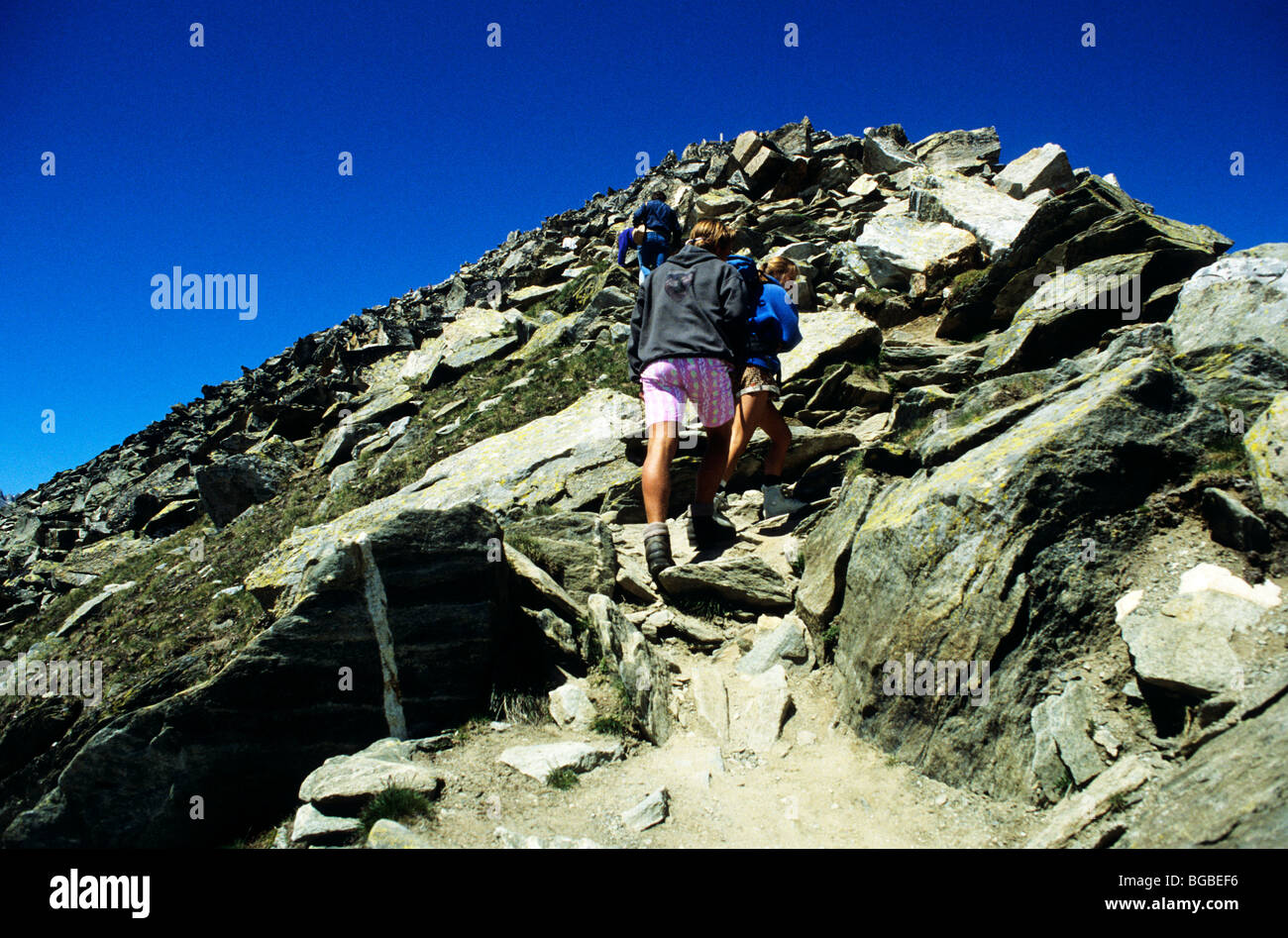 Group of young walkers walking up a very rocky hill path Stock Photo ...