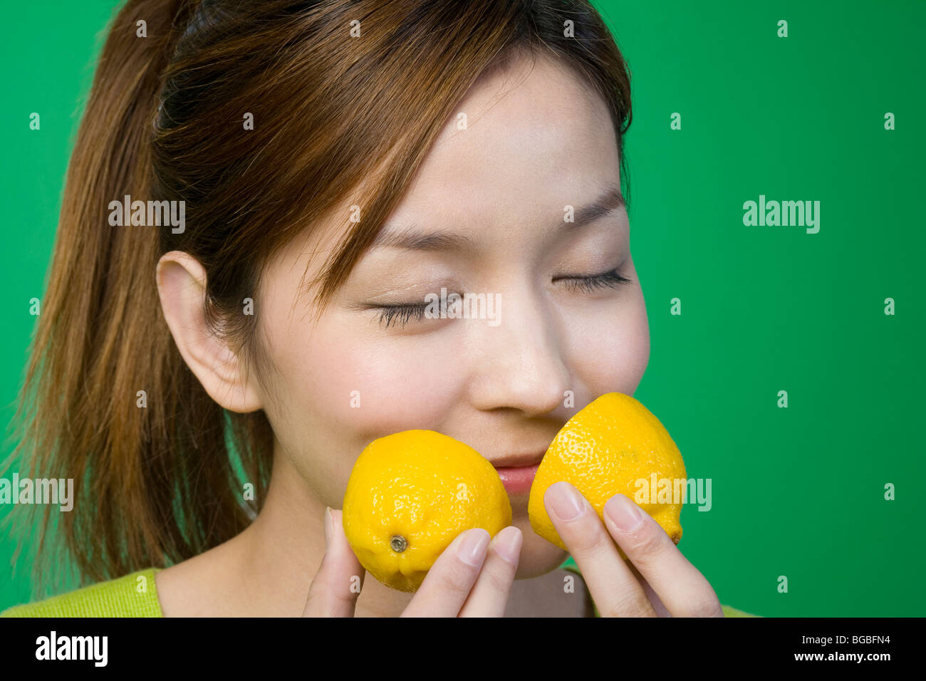 Woman in green smelling a lemon Stock Photo - Alamy