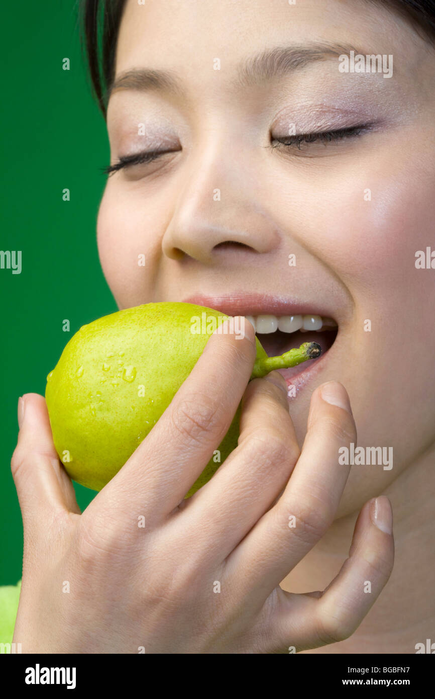 Woman in green eating a pear Stock Photo - Alamy