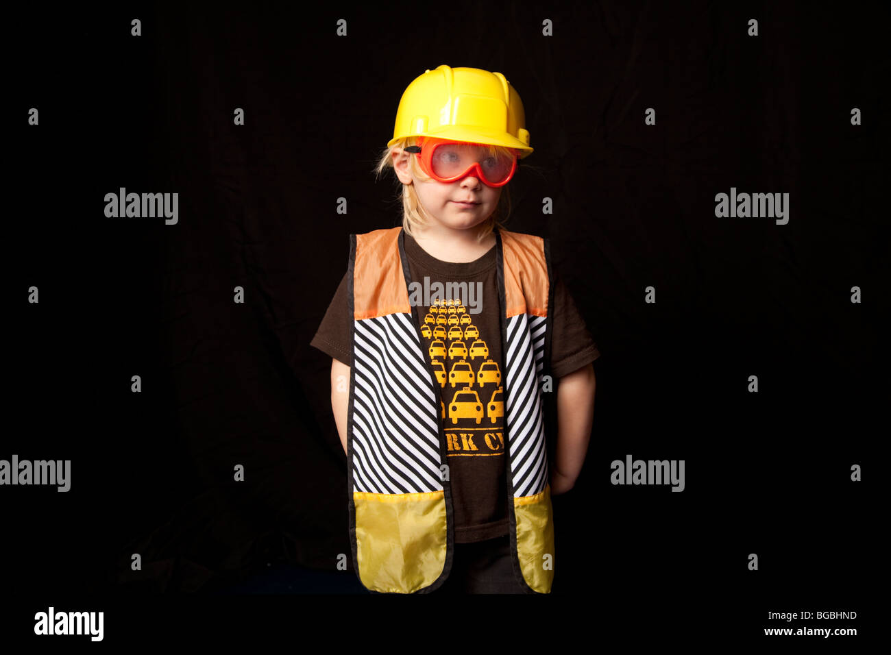 boy wearing construction worker costume against black background. child ...