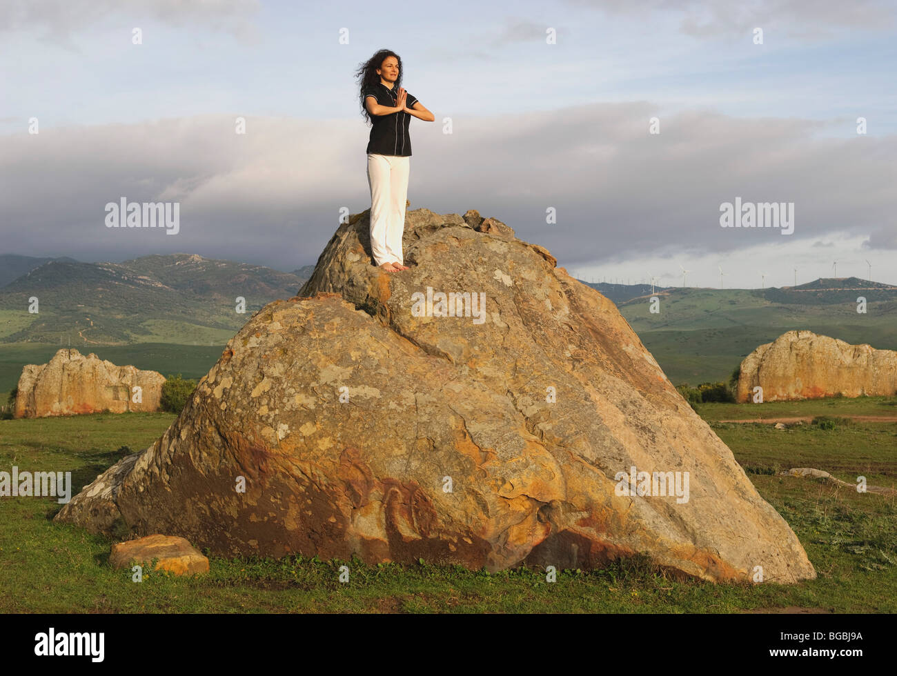 Woman standing on a rock and meditating Stock Photo - Alamy