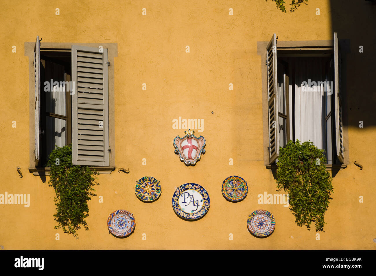 Windows and dishes on apartment building facade, Cherasco, Piedmont ...
