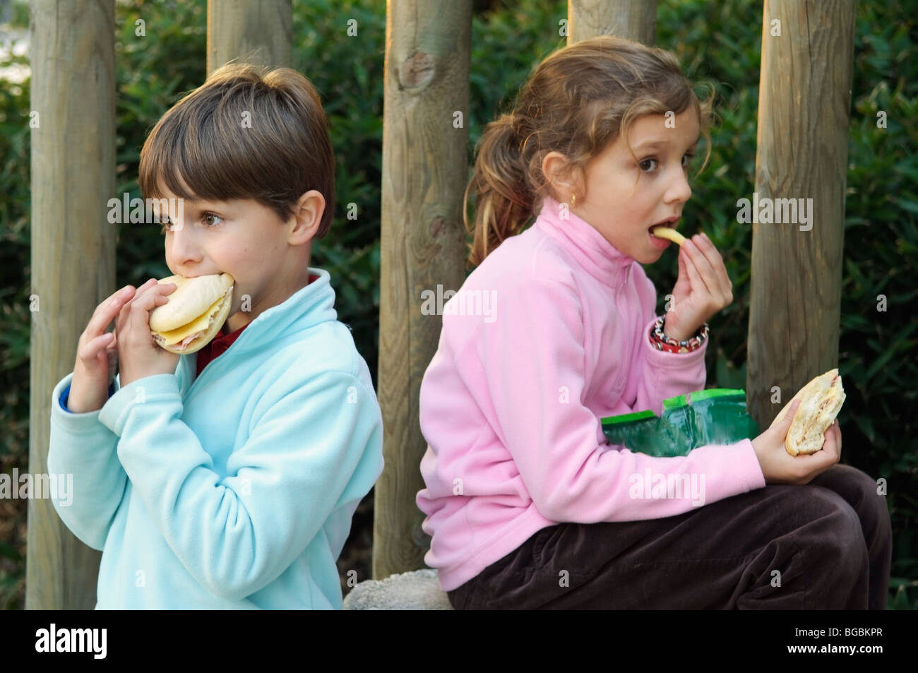 Girl and boy eating sandwiches Stock Photo - Alamy