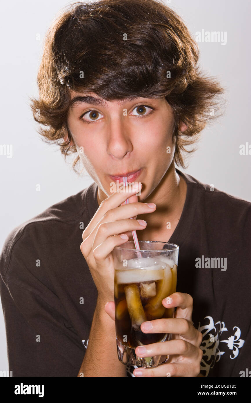 Teenage boy drinking soda from a glass with a straw, Studio, Portrait ...
